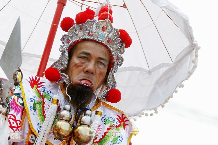 A worshipper, with steel hooks pierced through his cheeks